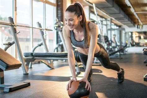 Smiling Young Fit Woman In Sportswear Doing Plank Exercise With Ball In