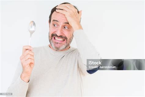 고립 된 배경 위에 실버 숟가락을 들고 수석 남자 머리에 손으로 강조 수치심과 깜짝 얼굴 충격 화가 좌절 두려움과 실수에 대 한