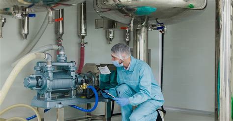 실험실 정장과 방독면을 쓴 과학자는 큰 강철 탱크 아래 엔진을 확인한다 사진 Unsplash의 약 이미지