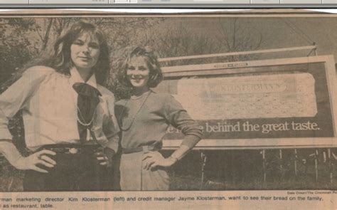 Two Women Standing Next To Each Other In Front Of A Sign