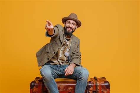 Man In Casual Travel Outfit With Hat Sitting On Vintage Suitcase Bright