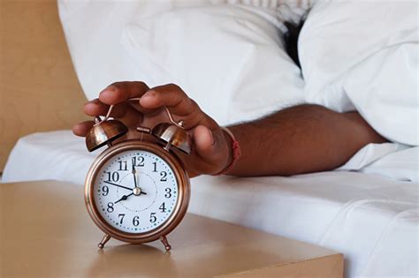 이미지 알아볼 수 없는 사람의 손이 호텔 더블 침대에서 침대 아래에서 뻗어 청동 금속 케이스 레트로 알람 시계 더블 벨 야간