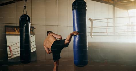 체육관에서 스포츠 훈련 중 복싱 가방을 차는 근육질의 파이터 사진 Unsplash의 종합격투기 이미지