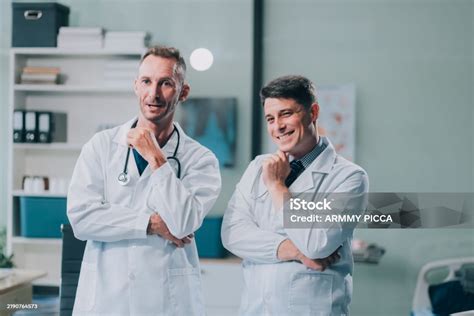 병원에서 태블릿과 다이어리를 들고 미소를 지으며 카메라를 바라보는 두 명의 헌신적인 의사의 초상화 흰 가운을 입은 두 명의 미소 짓는 의사가 사무실에서 일하고 카메라를 보고