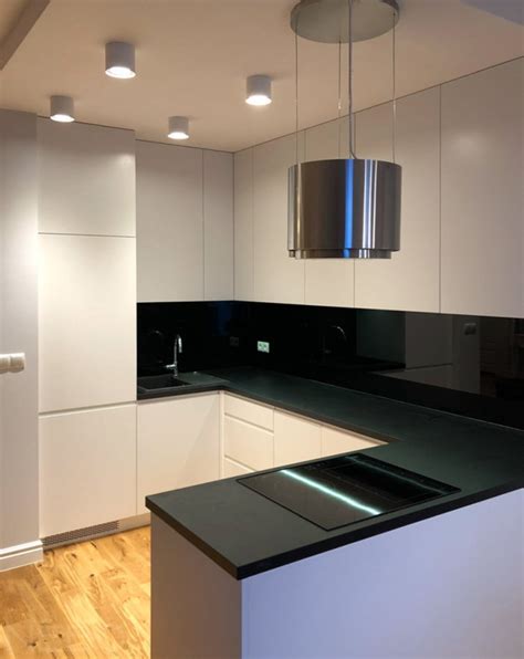 Угловая кухня с полуостровом с белыми матовыми фасадами черной столешницей и черным фартуком