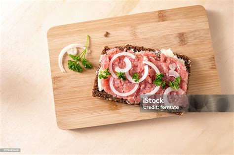 부엌 보드에 양파와 파슬리 장식을 곁들인 어두운 통밀 빵 한 조각에 메트 저지방의 다진 생 돼지 고기로 만든 독일 특산품 위에서 본 평면도 복사 공간 0명에 대한 스톡 사진