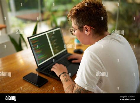 Transgender Web Developer Works On Laptop Programming In Modern Eco Office Focused Individual