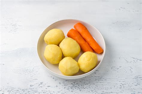 껍질을 벗긴 삶은 야채 감자 당근이 있는 하얀 접시는 하늘색 배경에 있다 야채 샐러드 조리 단계 감자 요리에 대한 스톡 사진 및 기타 이미지 Istock