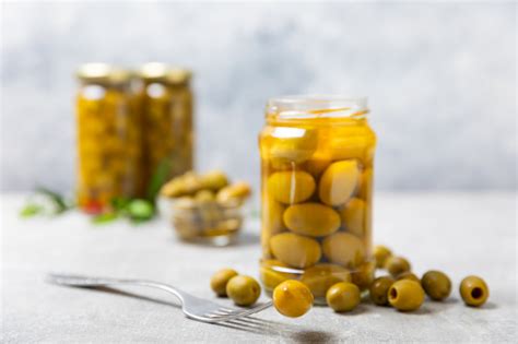 콘크리트 배경에 유리병에 담긴 올리브 항아리에 움푹 들어간 올리브 유리병에 절인 올리브 나무 배경에 마리나드 올리브 텍스트를