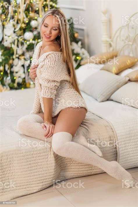 아름 다운 젊은 여 자가 입고 니트 흰색 스웨터 및 스타킹 새 해 나무 근처에 앉아 12월에 대한 스톡 사진 및 기타 이미지