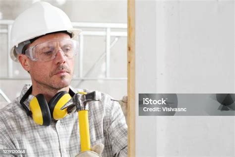 망치와 남자 건설 노동자는 내부 건물 현장에서 장갑 하드 모자 안경 및 청력 보호 헤드폰을 착용 벽에 판자 손톱 Diy에 대한 스톡 사진 및 기타 이미지 Istock