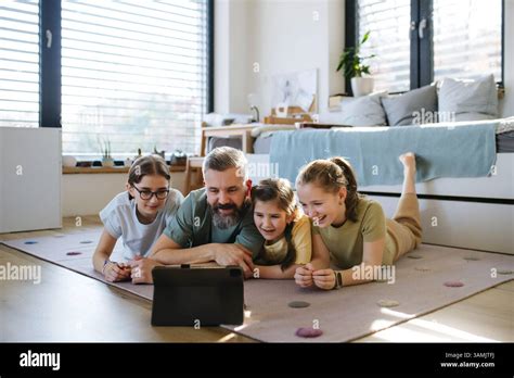Portrait Of Father With Three Daughters Watching Tv Show On Tablet