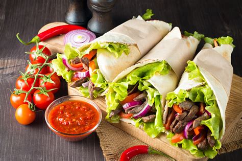 멕시코 샌드위치 음식 버 리 토 Fajita 타코 소박한 나무 바탕에 신선한 야채 닭고기 쇠고기 옥수수로 만든 포장의 사진 패스트 푸드 개념입니다 건강 한 점심 간식입니다