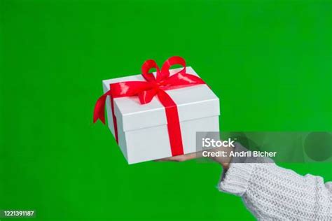 녹색 배경에 고립 된 빨간 리본으로 묶인 흰색 선물 상자를 들고 있는 여성의 손을 닫습니다 생일 선물에 대한 스톡 사진 및 기타 이미지 Istock