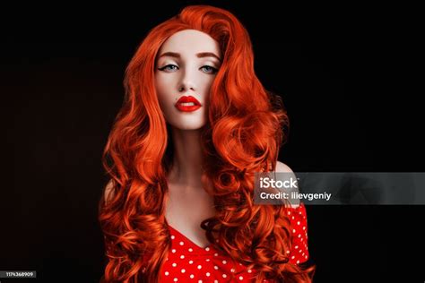 검은 배경에 창백한 피부와 빨간 입술빨간 머리 여자 복고풍 드레스에 구리 머리를 가진 소녀입니다 빨간 곱슬 가발 빨간 머리 여자입니다 긴 물결 모양의 가발 볼륨감 있는 곱슬