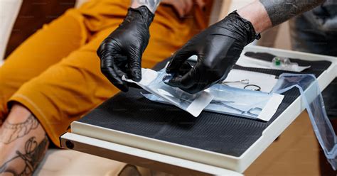 피어싱을 위해 멸균 장비를 여는 남자의 클로즈업 절차를 준비하는 피어싱 바디 피어싱 살롱 피어싱을 받는 여자 사진