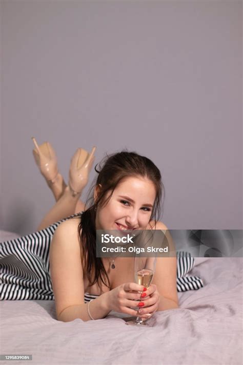 회색 침실의 침대에 샴페인 한 잔과 저녁 칵테일 드레스에 행복한 매력적인 갈색 머리 여자 애프터 파티 외로움 20 29세에 대한