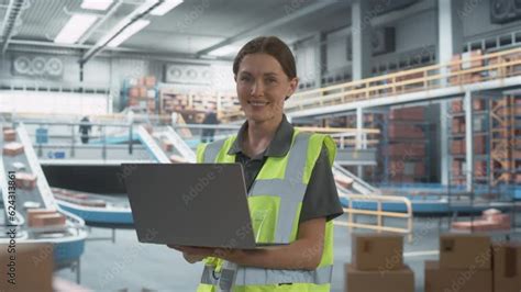 Modern Sorting Center Female Stocking Associate Uses Laptop Looking At Camera And Smiling