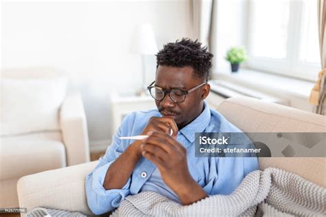 독감 알레르기 세균 감기 기침을 가진 아픈 사람의 초상화 고열과 독감이있는 담요 아래에 앉아 두통이있는 아픈 남자 휴식과 뜨거운 음료를 마시는 20 24세에 대한 스톡 사진