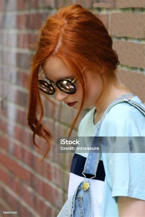 카메라를 보고 빨간 머리를 가진 예쁜 무디 슬픈 십대 소녀 청소년의 이미지 벽돌 벽에 의해 생각에 잃어버린 미소 빨간 머리 를
