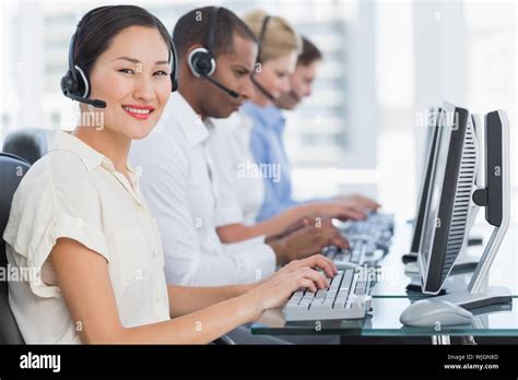 Side View Portrait Of Business Colleagues With Headsets Using Computers At Office Desk Stock