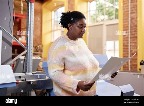 Portrait Of Young Black Woman Operating Printing Machine And Looking At