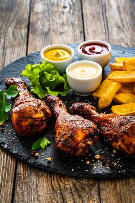 Roast Chicken Drumsticks And French Fries On Wooden Table Stock Image