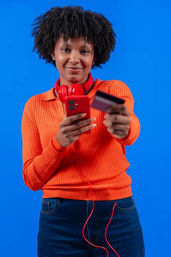 아프로이카 계 미국인 여자가 파란색 배경에 전화와 신용 카드로 온라인 쇼핑을 합니다 구매에 대한 스톡 사진 및 기타 이미지 구매 금융 명랑한 Istock