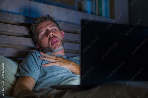 Man Alone In Bed Playing Cybersex Using Laptop Computer Watching Porn Sex Movie Late At Night
