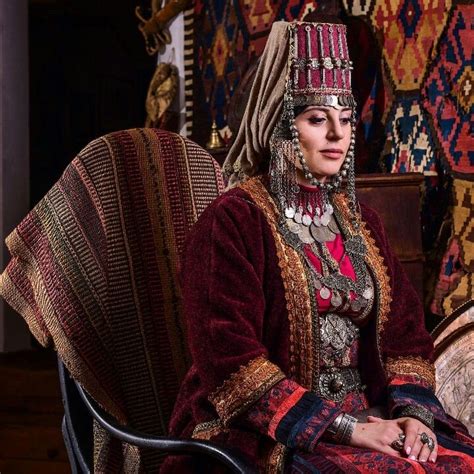 A Woman Sitting In A Chair Wearing An Elaborate Headdress And Jewelry On Her Head