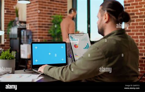 Startup Employee Analyzing Business Charts And Greenscreen On Laptop At Office Desk Looking At