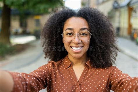 Smiling Woman With Curly Hair And Glasses Taking A Selfie Outdoors On A