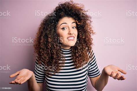 곱슬 머리와 피어싱 캐주얼 줄무늬 티셔츠를 입고 젊은 아름다운 여성은 팔과 손을 들고 단서와 혼란 표정을 의심 개념 T 셔츠에 대한 스톡 사진 및 기타 이미지 Istock