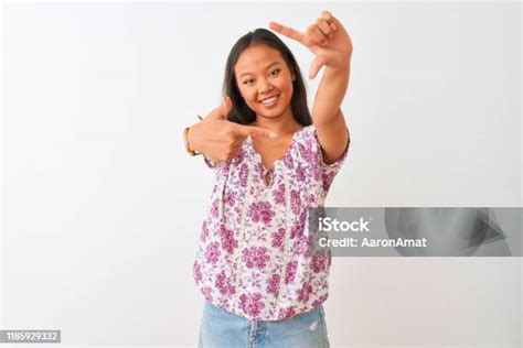 편안한 꽃무늬 티셔츠를 입은 젊은 중국 여성이 행복한 얼굴로 손과 손가락으로 프레임을 만드는 고립 된 흰색 배경 위에 서 있습니다 창의력과 사진 개념 T 셔츠에 대한 스톡