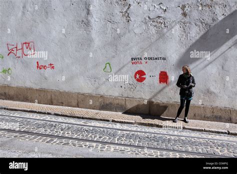 Woman Standing On Sloping Street In Lisbon With Tram Lines And Wall