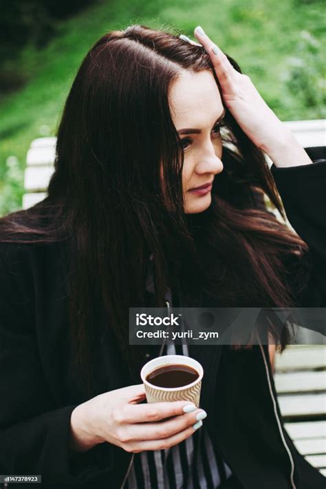 까만 커피의 종이 컵을 들고 거리에서 보이는 화려한 검은 눈 갈색 머리 검은 코트와 줄무늬 흑백 셔츠를 입고 매력적인 젊은 여자 5월에 대한 스톡 사진 및 기타 이미지