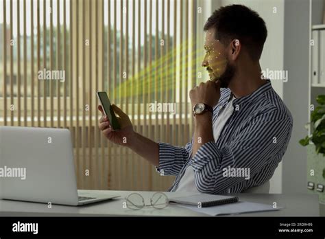 Man Using Smartphone With Facial Recognition System In Office Security Application Scanning His