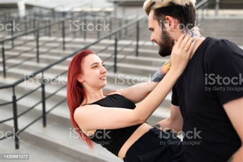 검은 옷을 입은 세련된 커플이 공원에서 산책하고 포옹합니다 계단의 배경에 포옹하는 힙스터의 사랑스러운 커플 청소년 사랑 및 라이프 스타일 개념 2명에 대한 스톡 사진 및