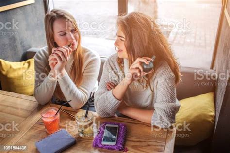 명랑 하 고 좋은 젊은 여자 냄새 Parfume 병에서 그들은 서로 모양과 미소 모델 내부 테이블에 앉는 다 우정에 대한 스톡