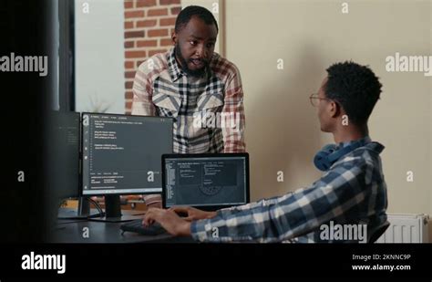 software developer sitting at desk with multiple screens and laptop running code stock video