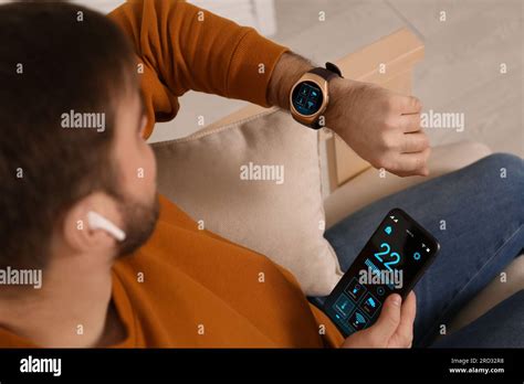 Man Setting Smart Home Control System Via Smartwatch And Mobile Phone Indoors App Interface