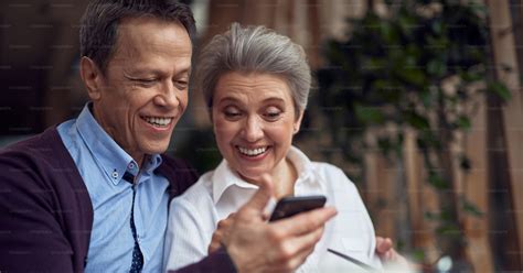 즐거운 회의 허리 위로 초상화 행복한 미소 짓는 노인 남자가 여자를 껴안고 있는 동안 그들은 휴대 전화를보고 카페에 앉아 사진 Unsplash의 장년 커플 이미지