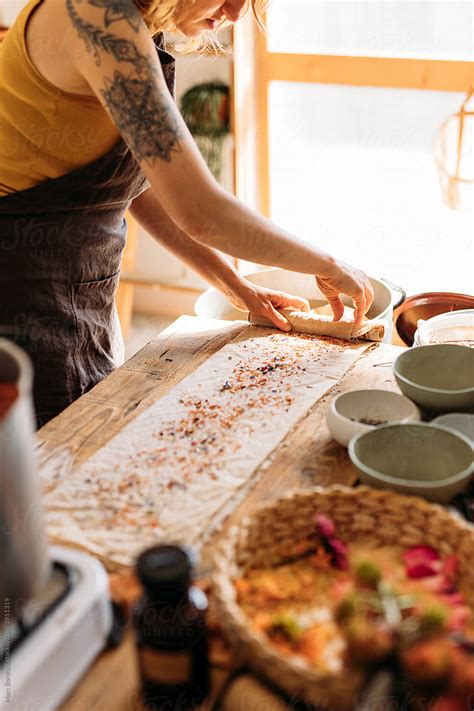 A Womans Hands Rolling A Roll Of Fabric Over A Table By Stocksy