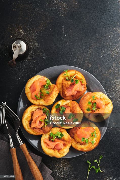 요크셔 푸딩 연어와 무 마이크로 그린 반찬이 있는 전통적인 영국 요크셔 푸딩은 어두운 회색 접시와 어두운 배경 테이블에 놓입니다