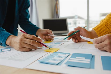 Ux 개발자와 Ui 디자이너가 현대 사무실에서 고객 요약 및 색상 코드와 함께 테이블에 모바일 앱 인터페이스 와이어프레임 디자인에 대해 브레인스토밍합니다 크리에이티브 디지털