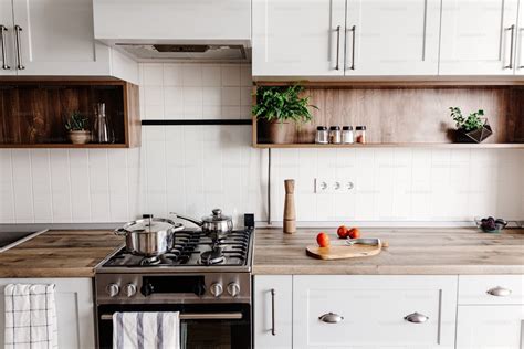 강철 오븐 냄비 야채 후추 향신료 나무 테이블 위에 기름을 곁들인 나무 도마에 칼이 있는 현대적인 주방에서 음식을 요리합니다 가정 음식 그레이 색상의 세련된