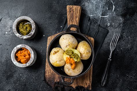 Papas Arrugadas Canary 섬은 프라이팬에 제공되는 녹색과 빨간색 소스로 감자를 주름 잡았습니다 검은 배경 위쪽 보기 파파스 아루가다스에 대한 스톡 사진 및