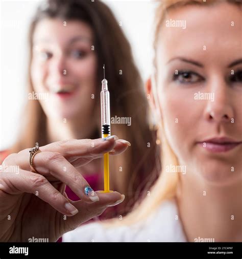 Syringe Examination By A Healthcare Worker Observed By An Apprehensive Individual Stock Photo