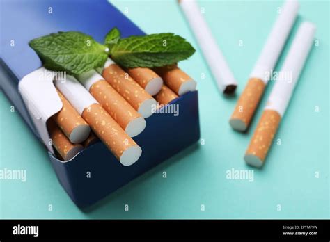 Pack Of Menthol Cigarettes And Mint On Turquoise Background Closeup