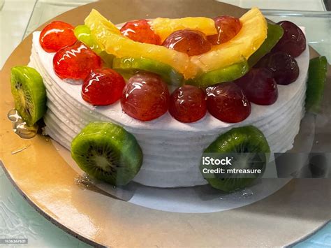 원형 케이크 보드에 디저트 크림 얇게 썬 키위 파인애플 및 붉은 포도 장식으로 덮인 원형 케이크 보드의 베이커리 디스플레이의 클로즈업 이미지 전경에 초점 반면에 대한 스톡